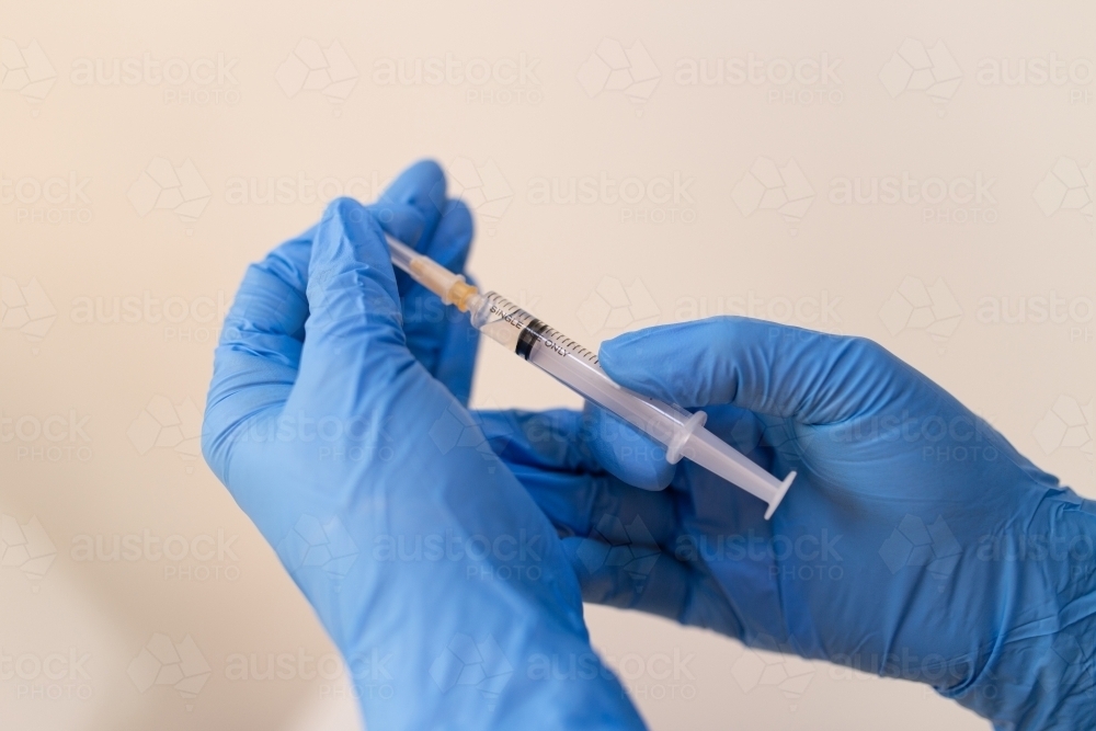 Image of Close up shot of a syringe being inserted to a medicine glass ...