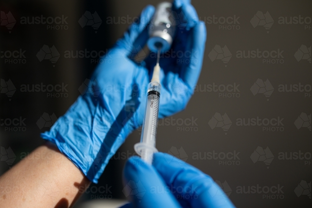 Image of Close up shot of a syringe being inserted to a medicine glass ...