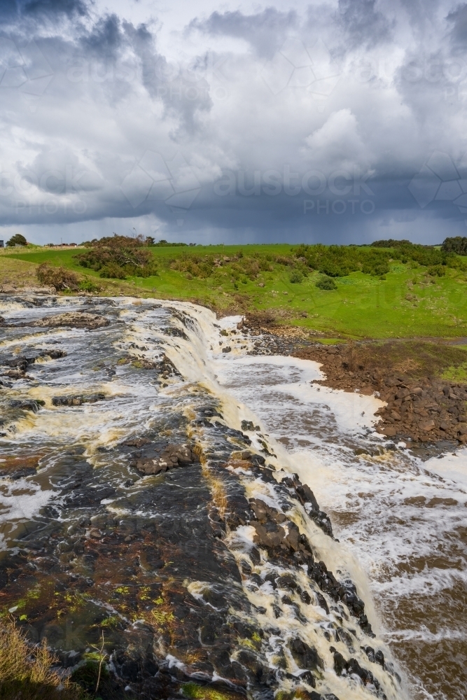 Image of Close up view of a wide rocky waterfall with dramatic storm ...