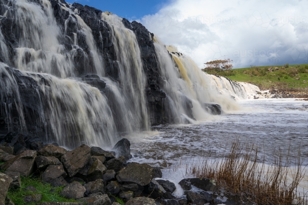 Image of Close up view of a wide rocky waterfall with dramatic storm ...