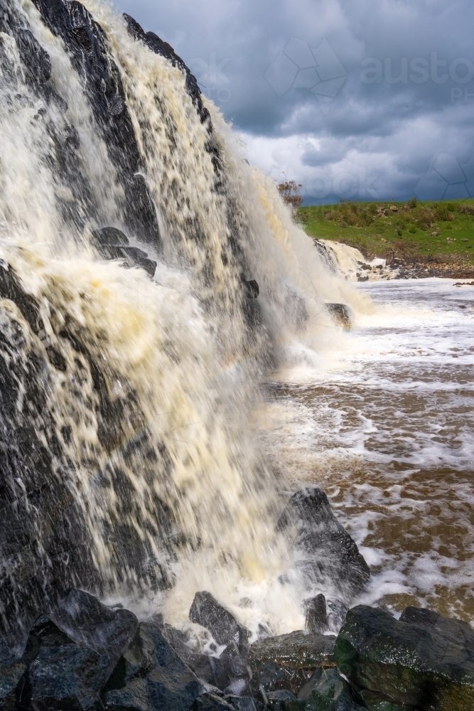 Image of Close up view of a wide rocky waterfall with dramatic storm ...