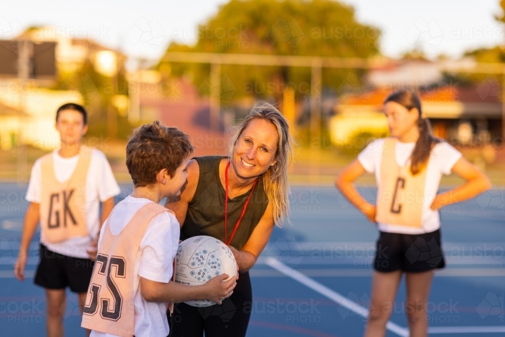 Image of coach of school netball team interacting with child on court ...