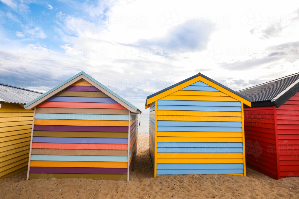 Image of Colorful striped beach huts under partly cloudy sky at ...
