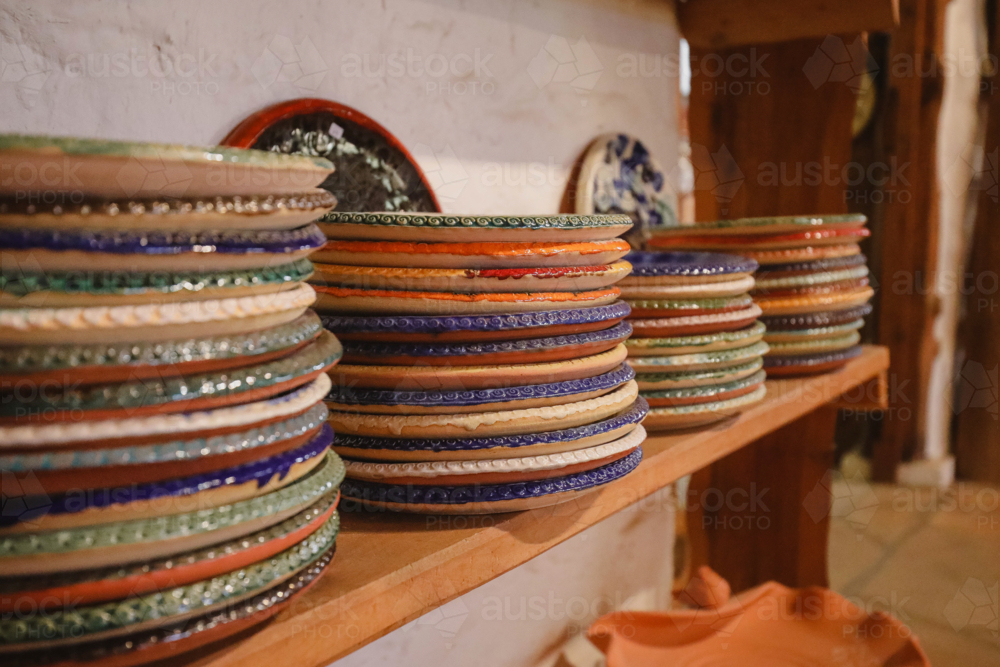 Image of Colourful Handcrafted Ceramic Plates Stacked on Wooden Shelf ...