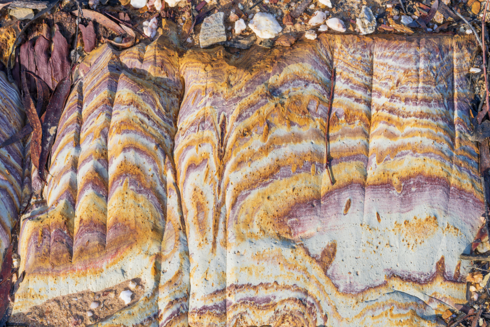 Image of Colourful patterns in eroded slate deposits in a creek bed ...