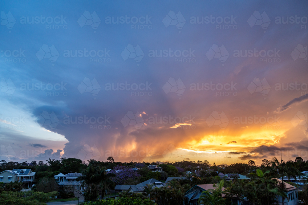 Image of Colourful sunset storm clouds approaching suburban houses ...