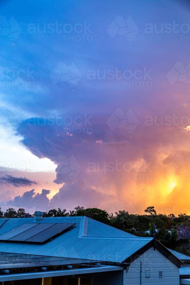 Image of Colourful sunset storm clouds approaching suburban houses ...
