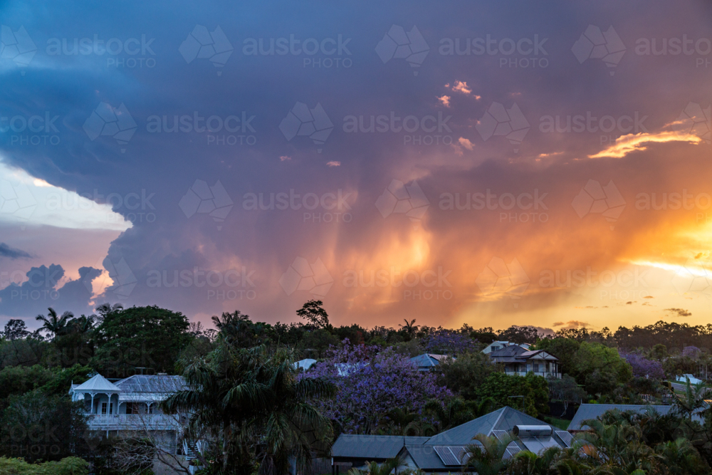 Image of Colourful sunset storm clouds approaching suburban houses ...