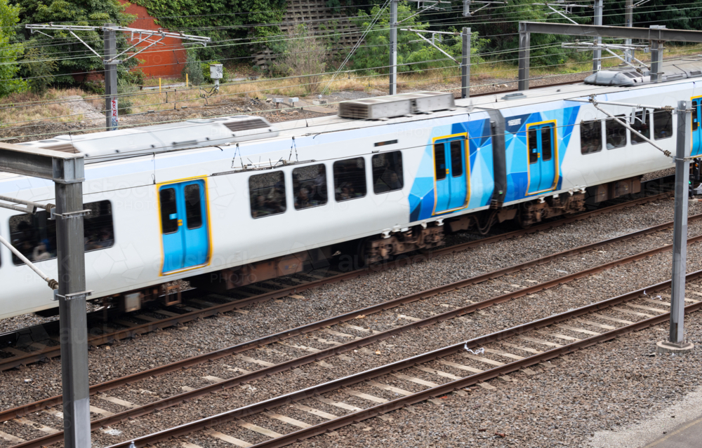 Image of commuter train going past railway tracks - Austockphoto