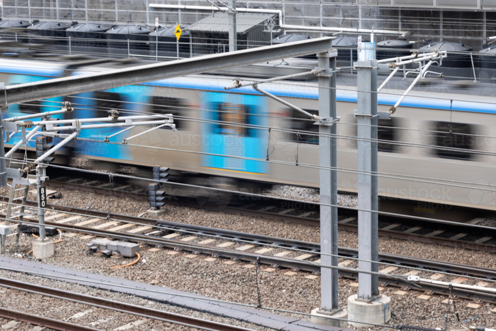 Image of commuter train going past railway tracks - Austockphoto