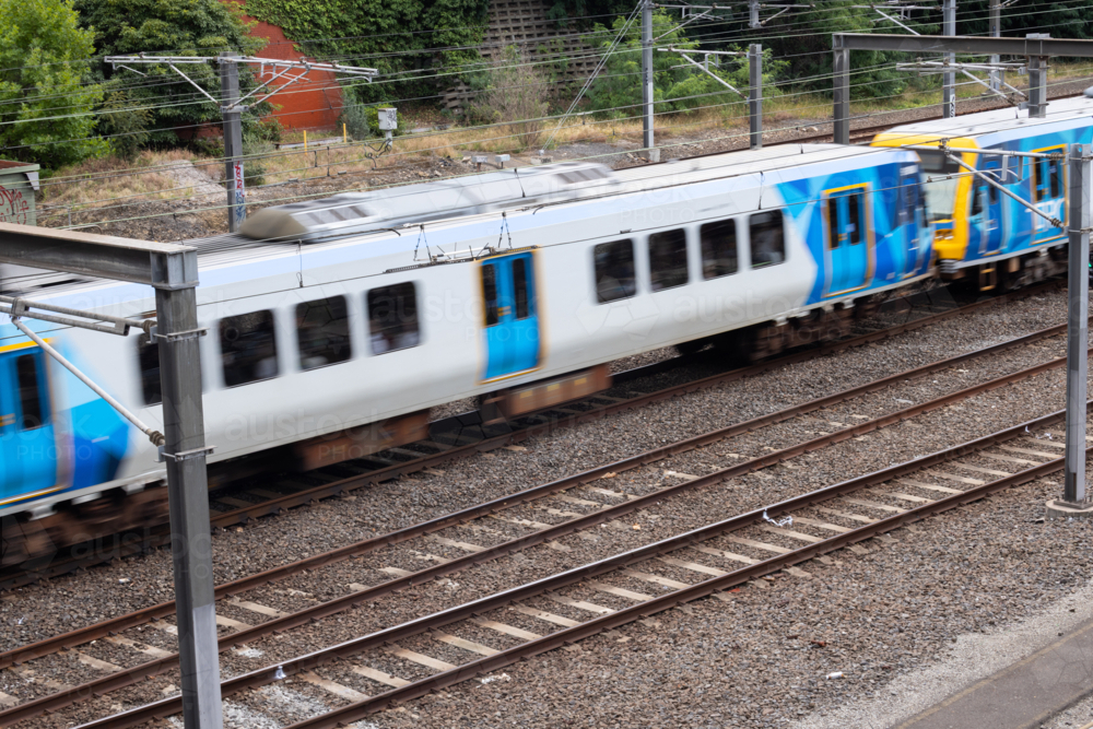 Image of commuter train going past railway tracks - Austockphoto