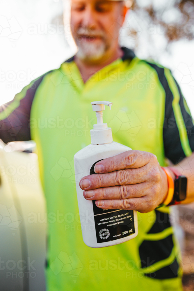 Image of Construction worker on a blurry background holding sunscreen ...
