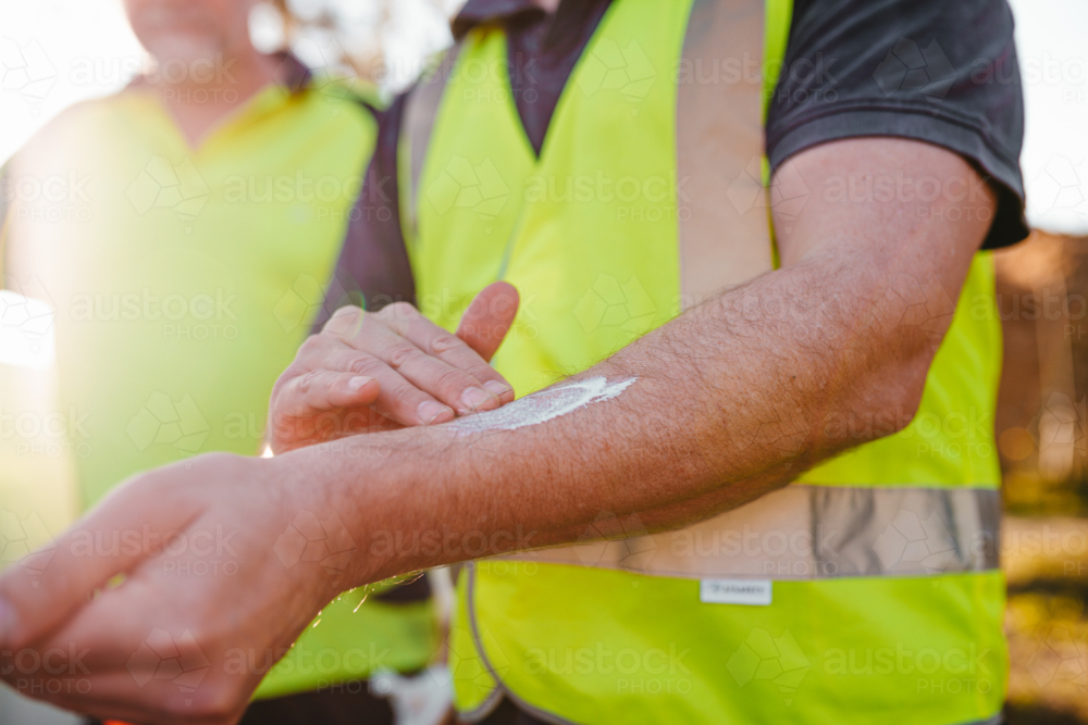 Image of Construction worker on a blurry background rubbing sunscreen ...