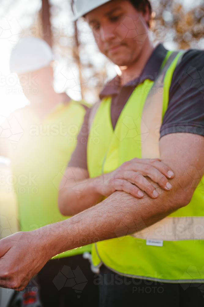 Image of Construction worker on a blurry background rubbing sunscreen ...