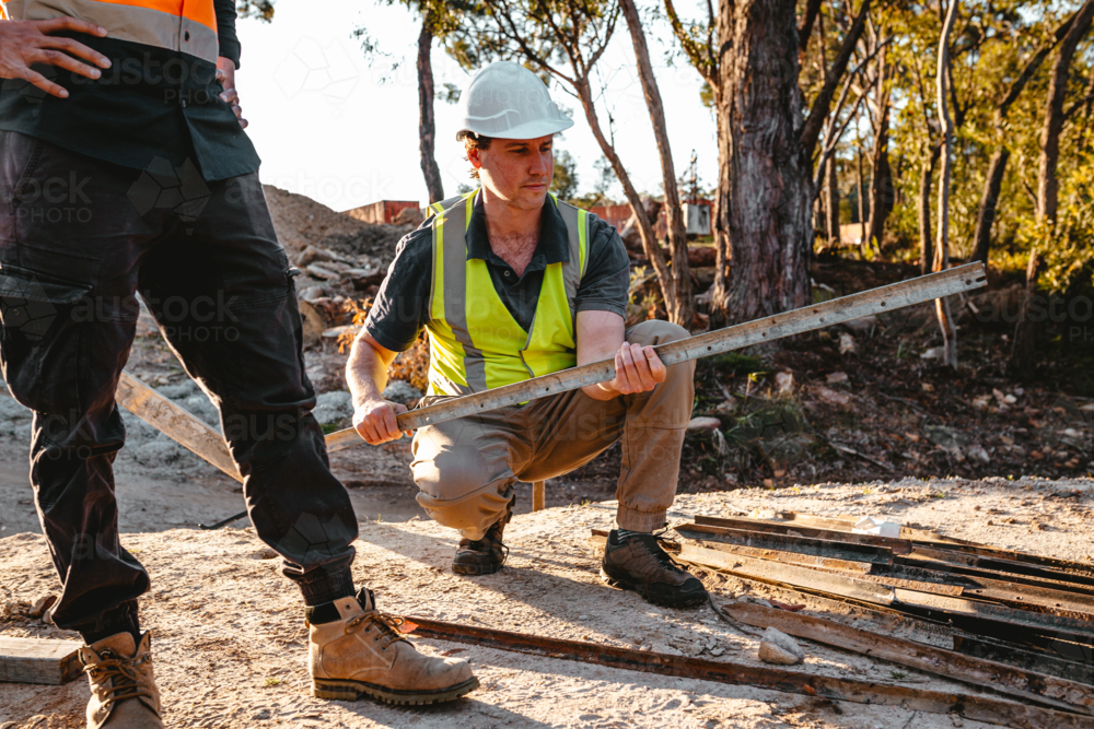 Image of Construction worker sorting metal stakes on the ground at the ...