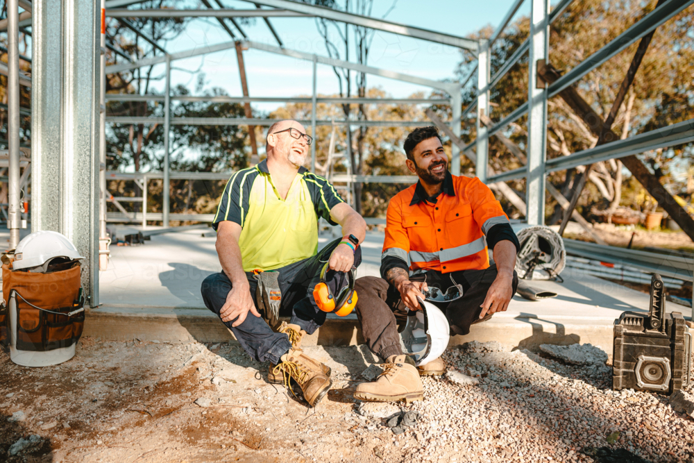Image of Construction workers sitting on the cemented floor on worksite ...