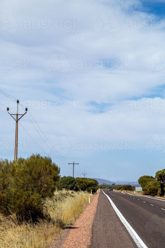 Image of Country bitumen highway and powerlines - Austockphoto