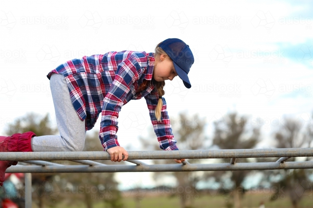 Image of Country girl playing on old climbing frame on farm - Austockphoto