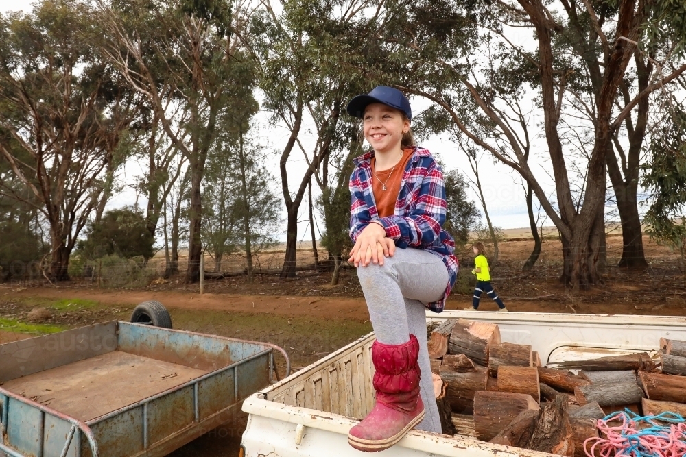 Image of Country girl standing on back of old work ute on wood cutting ...