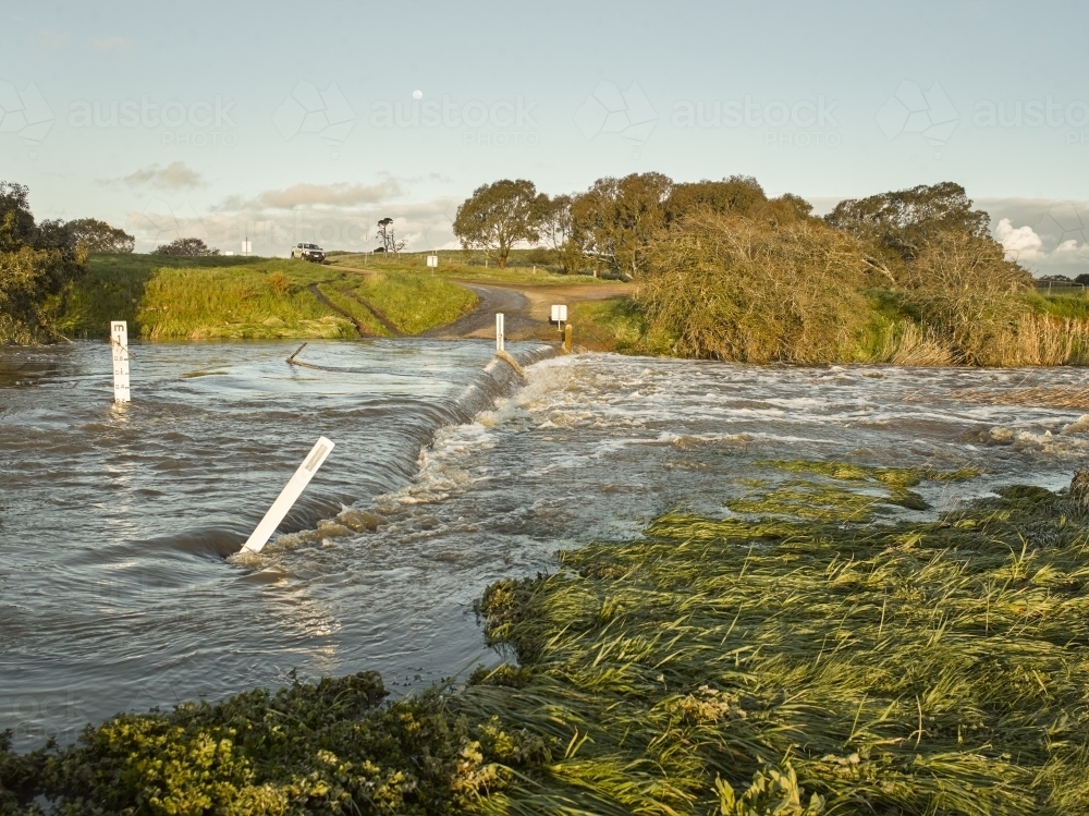Image of Country road leading through flooded causeway - Austockphoto