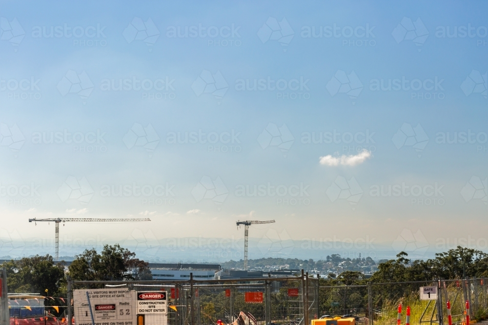 Image of Cranes in distance and construction sign fencing in foreground ...