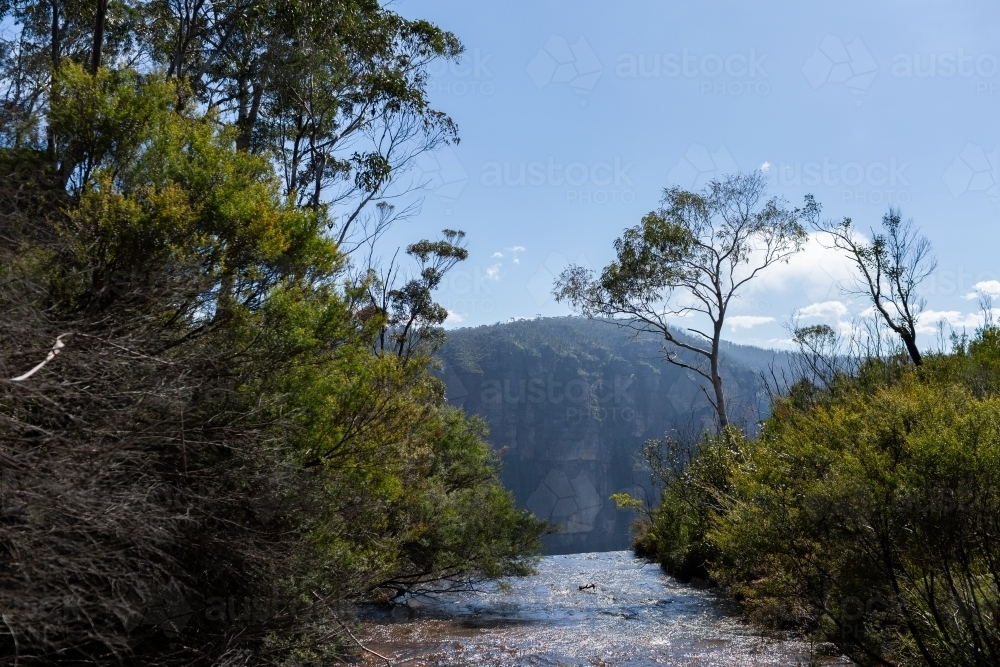 Image of Creek flowing through bushland over edge of cliff to waterfall ...