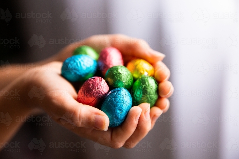 Image of cupped hands holding colourful Easter eggs - Austockphoto