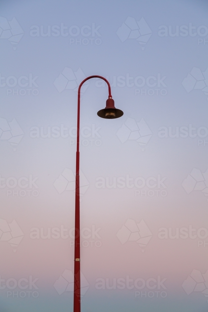 Image of Curved red lamp post against pastel gradient of dusk sky ...