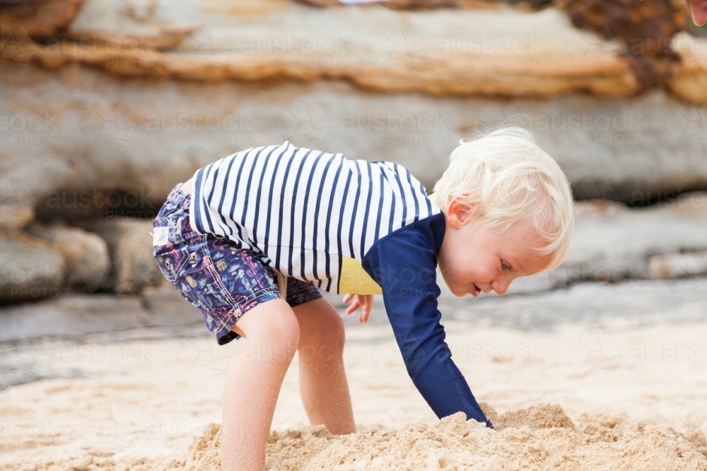 Image of Cute little boy playing in the sand at the beach - Austockphoto