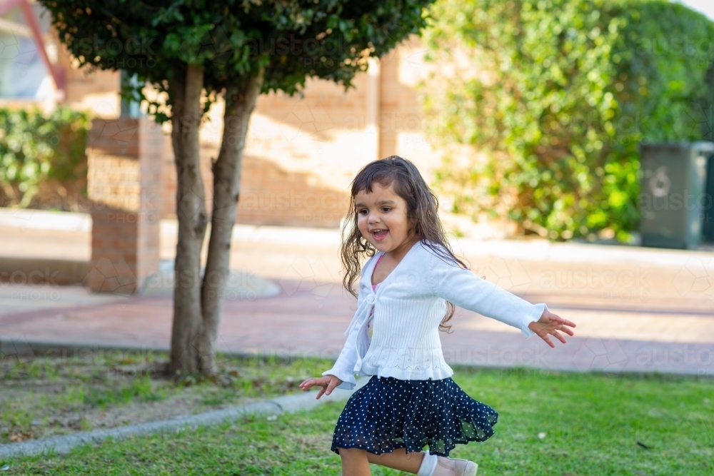 Image of Cute little girl twirling around outside - Austockphoto