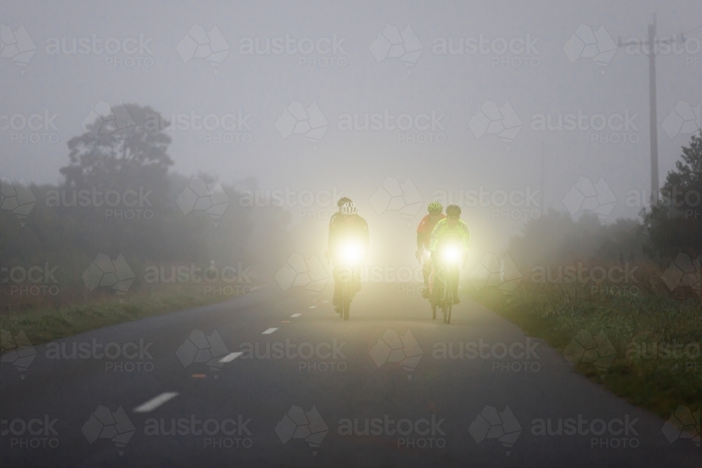 Image of Cyclists riding through heavy fog in the early morning ...