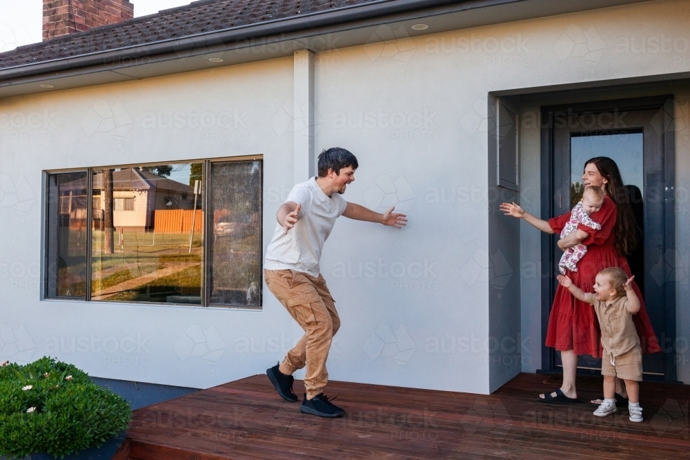 Image of Dad getting home to family running to hug wife and children ...