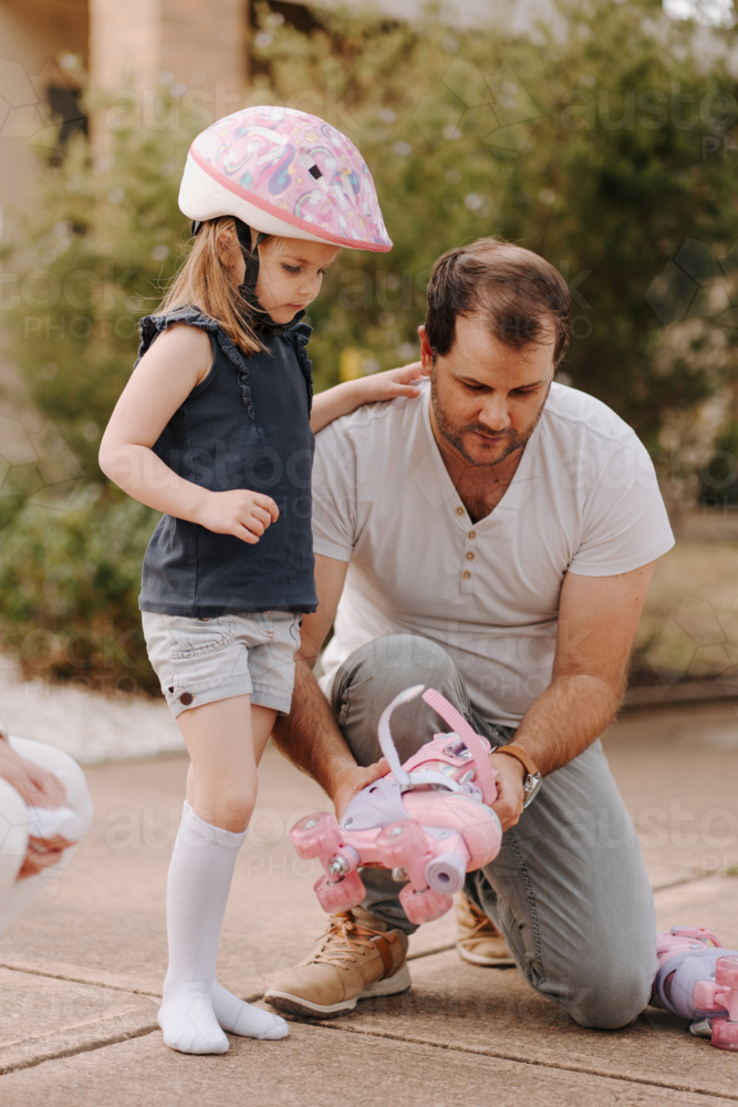 Image of Dad helping daughter get into her roller skate gear ...