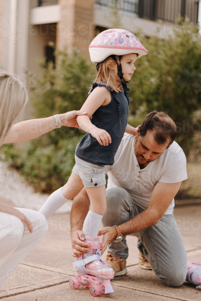 Image of Dad helping daughter get into her roller skate gear ...