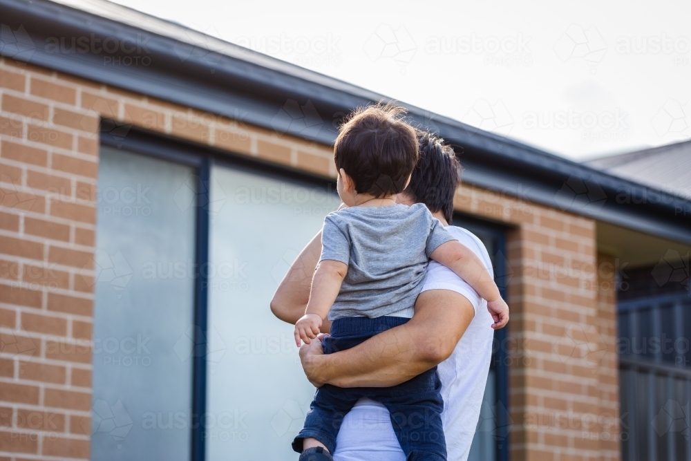 Image of Dad holding toddler boy standing outside home - Austockphoto
