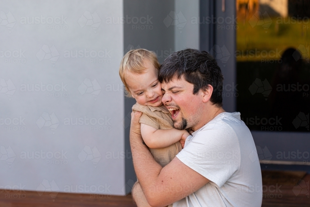 Image of Dad hugging two year old son outside of home in big bear hug ...