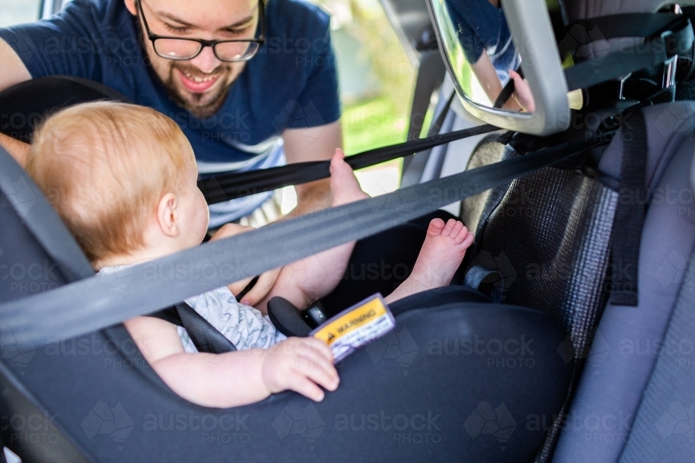 Image of Dad putting baby in rear facing car seat - Austockphoto