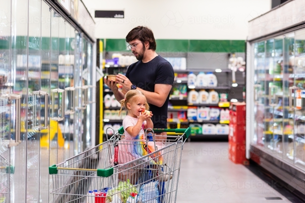 Image of Dad with toddler in shopping trolley buying groceries at shops ...