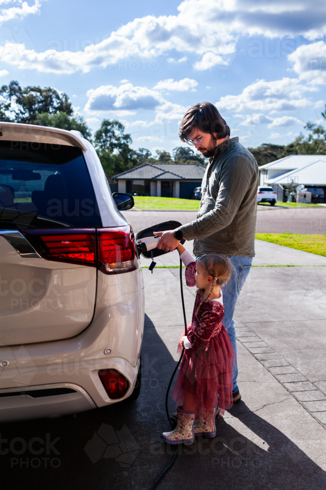 Image of Dad with young daughter unplugging hybrid ev vehicle together ...