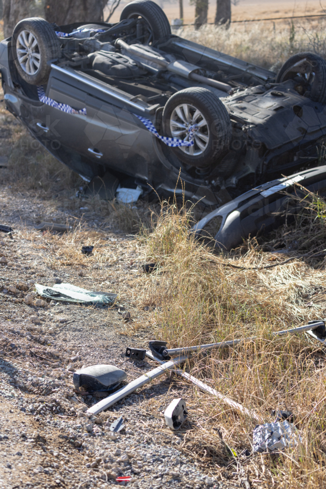 Image of Damaged and overturned car with debris on the roadside ...
