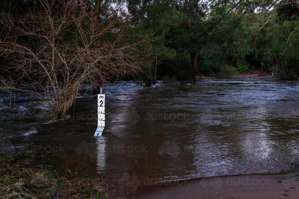 Image of damaged flood water level marker in creek at nightfall ...