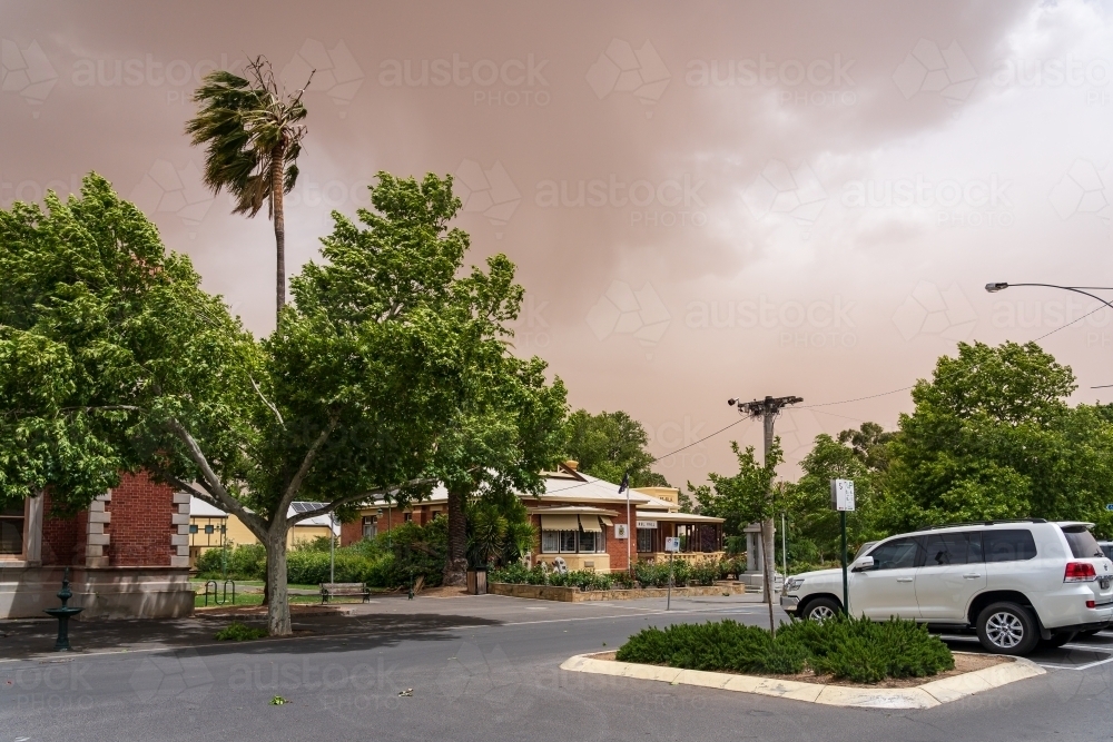Image of Dark dust filled clouds over a rural streetscape with trees ...