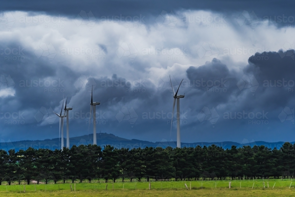 Image of Dark stormy skies hovering over tall wind turbines - Austockphoto