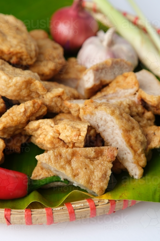 Image of Deep fried Cha Lua slices served on a banana leaf in a woven ...