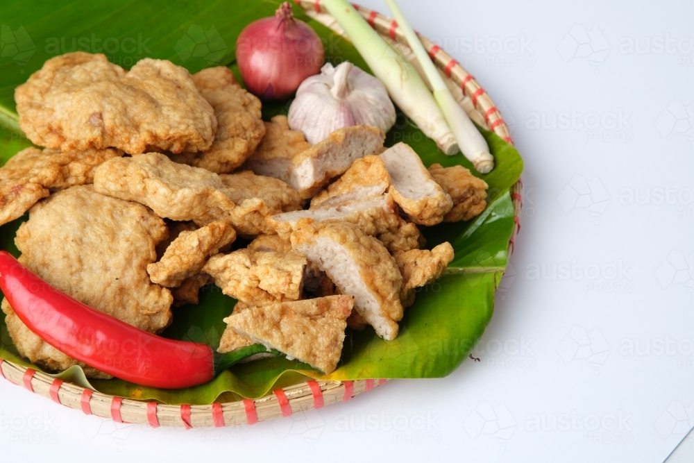 Image of Deep fried Cha Lua slices served on a banana leaf in a woven ...