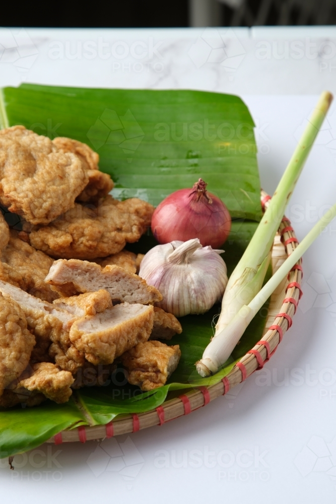 Image of Deep fried Cha Lua slices served on a banana leaf in a woven ...