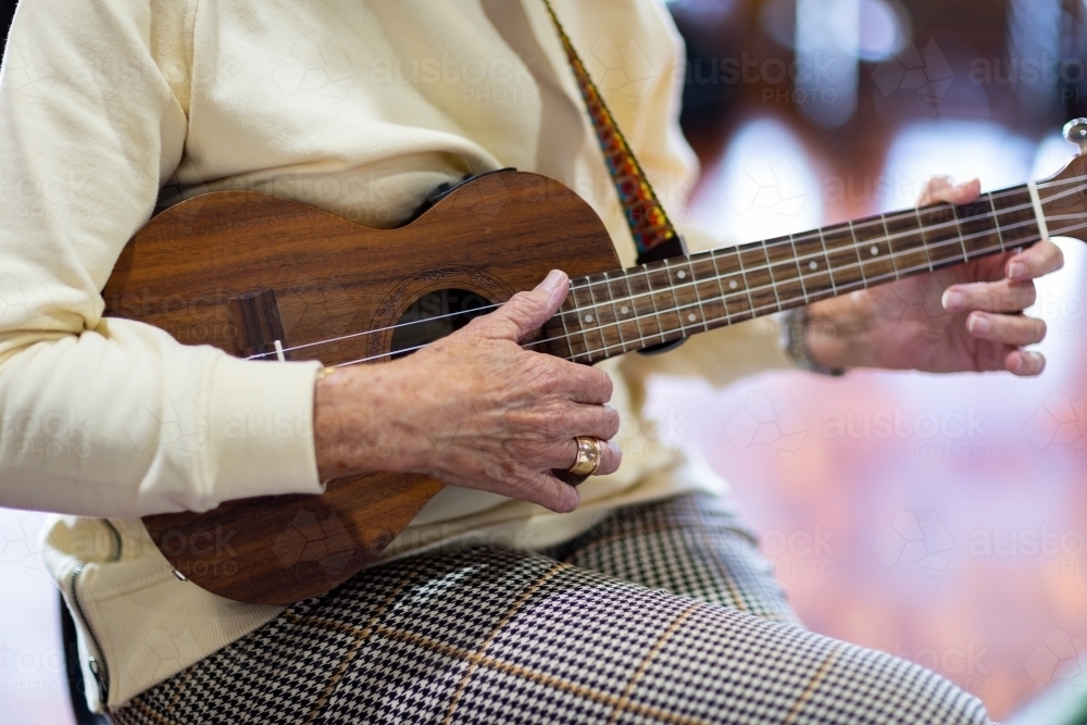 Image of detail of older lady playing ukulele - Austockphoto