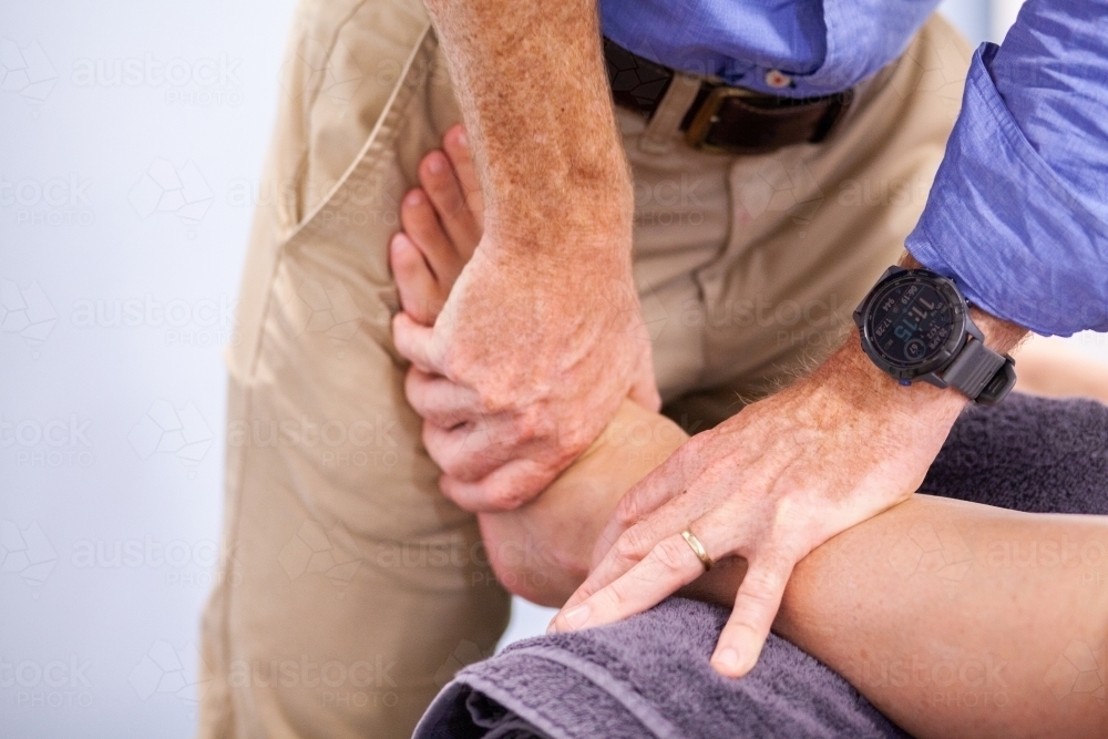Image of Detail of physio hands working on strengthening woman's ankle ...