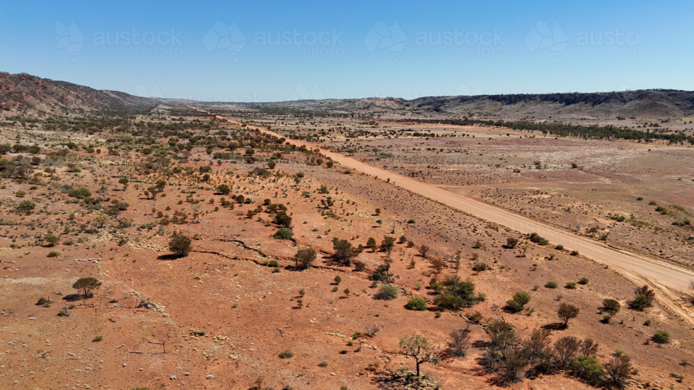 Image of Dirt road through the barren outback ranges - Austockphoto