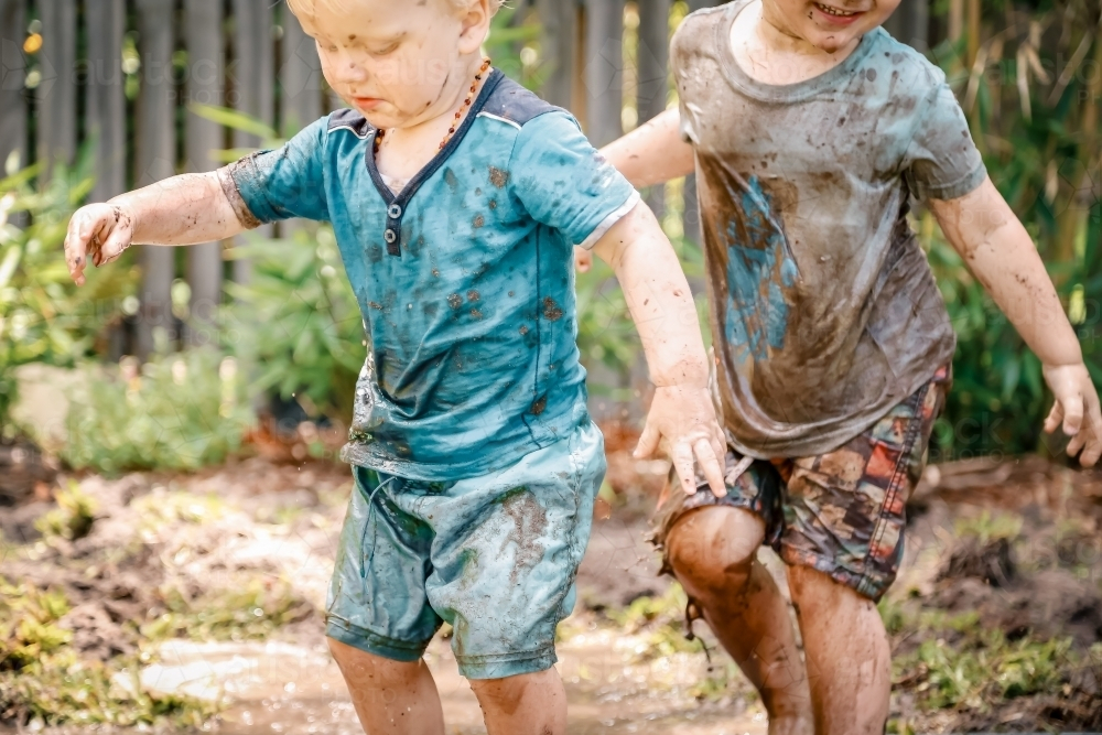 Image of Dirty children playing in muddy puddle - Austockphoto